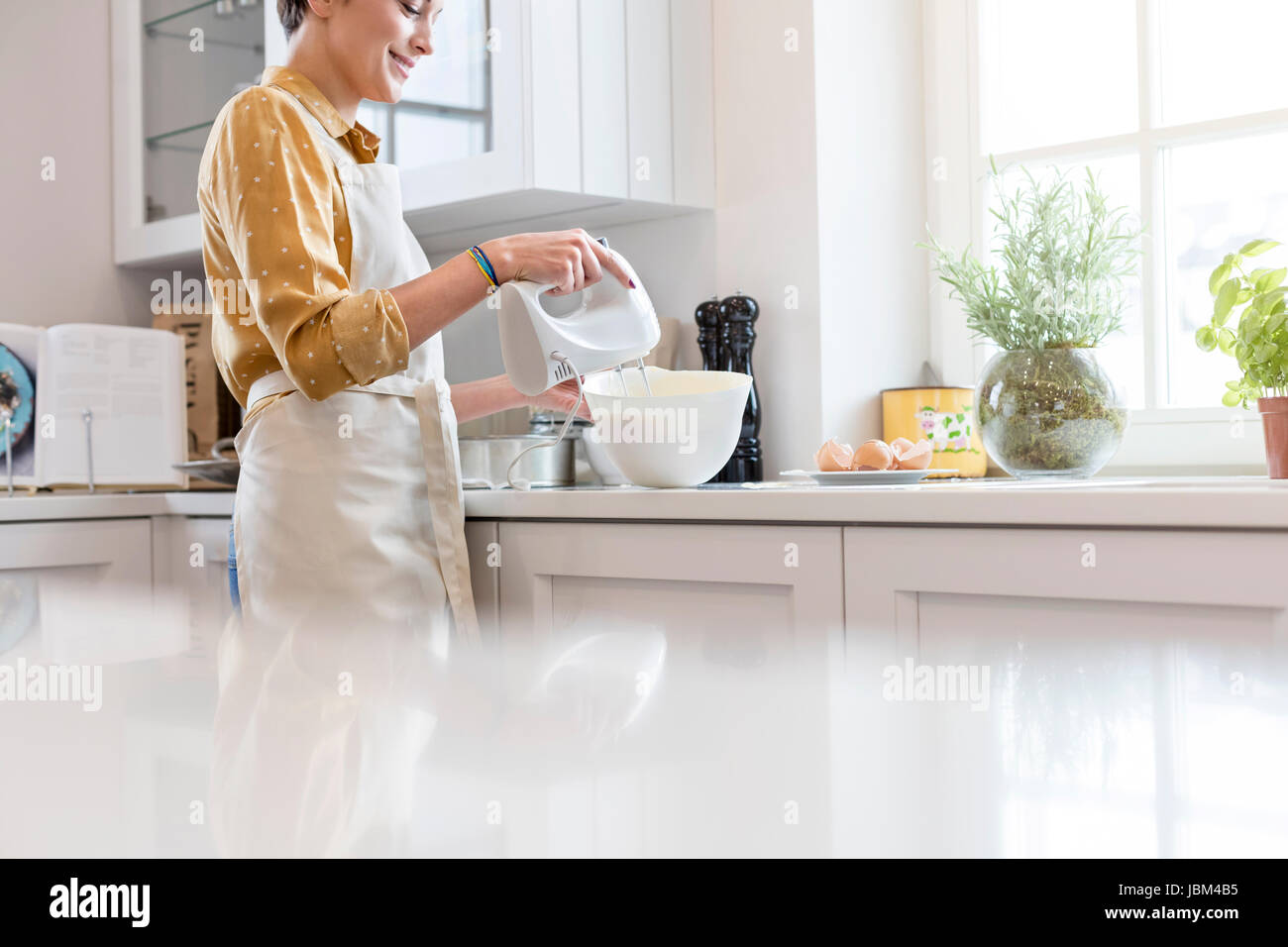 Woman baking, using electric hand mixer in kitchen Stock Photo - Alamy