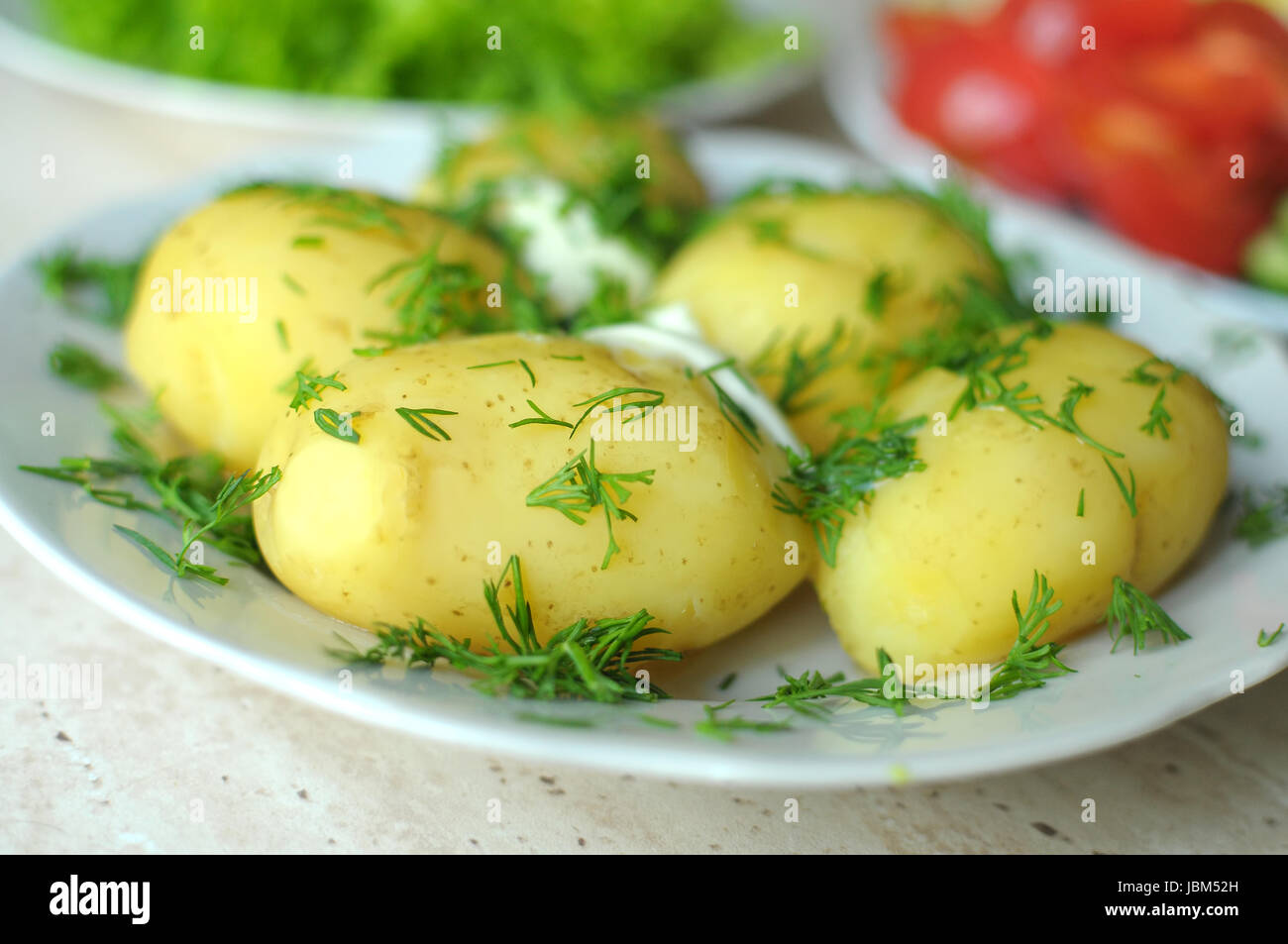 Fresh organic vegetables and boiled new potatoes on the plates on the ...