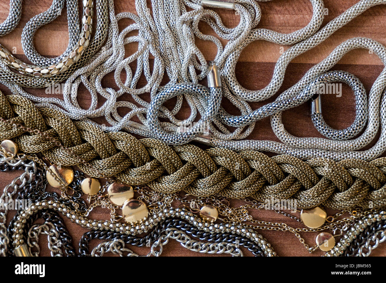 Mix of different size, color and texture chains on wooden background ...