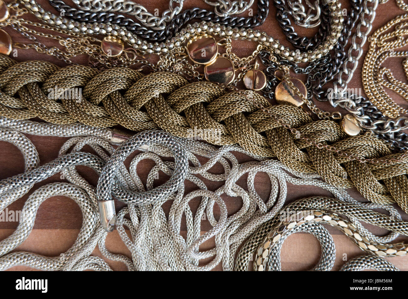 Mix of different size, color and texture chains on wooden background ...