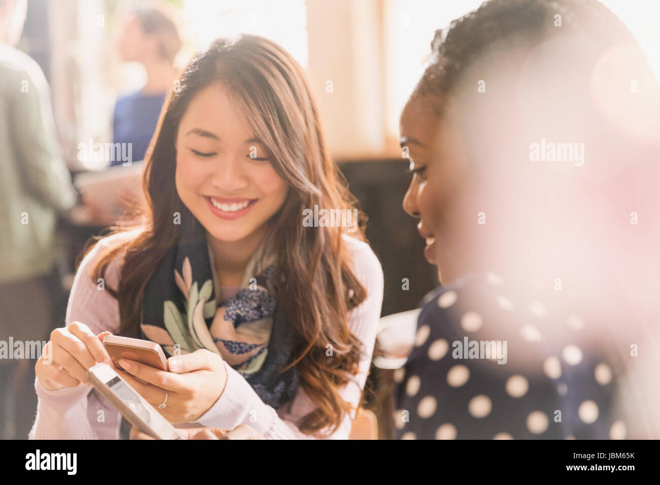 Female friends texting with cell phones in cafe Stock Photo - Alamy