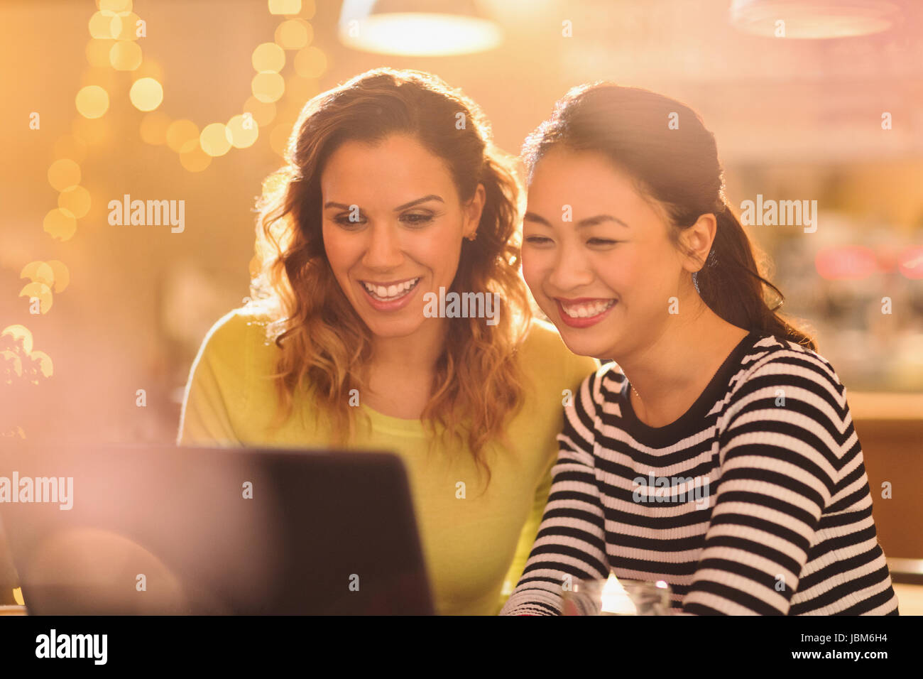 Smiling women friends using laptop Stock Photo - Alamy