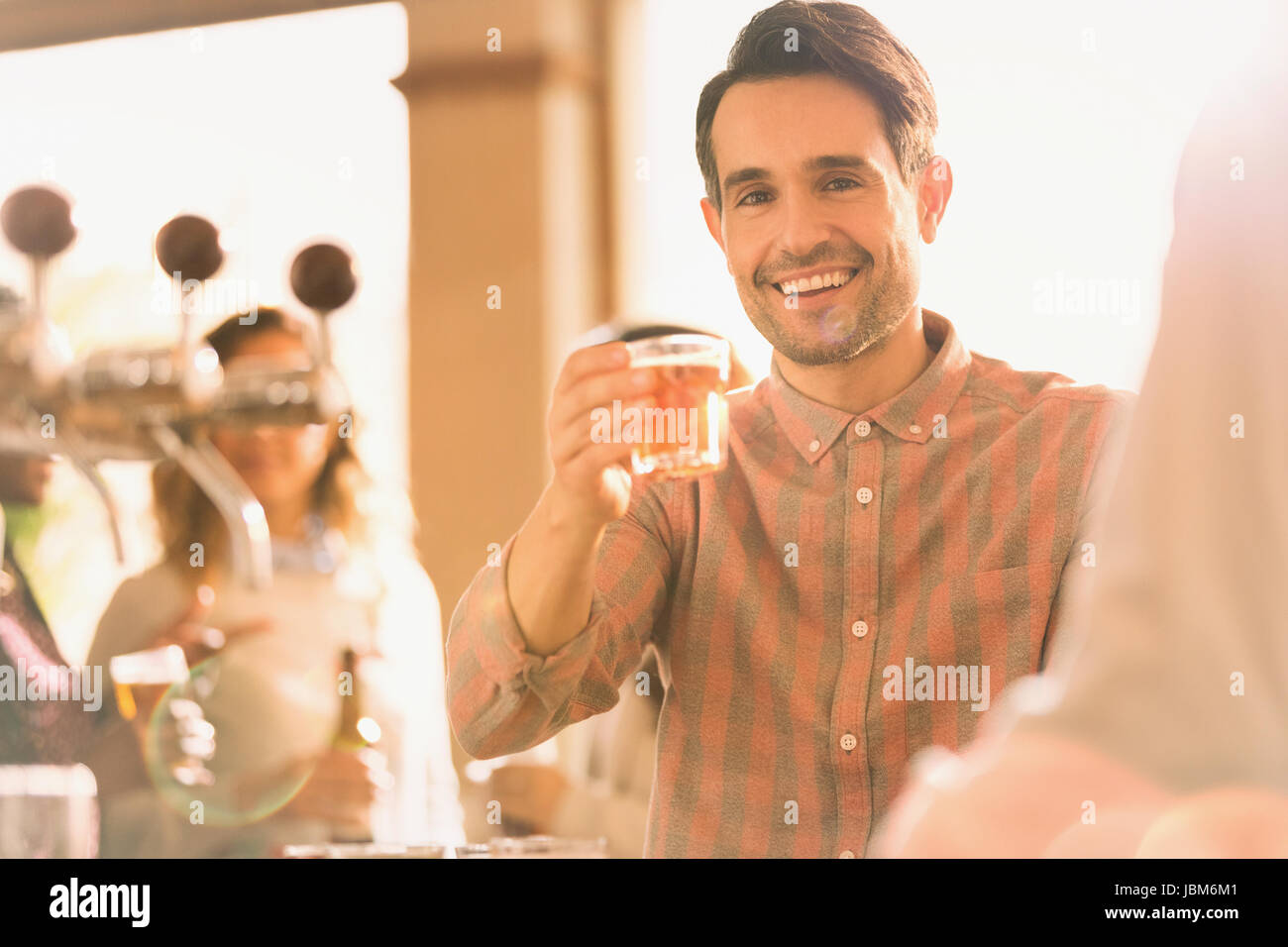Portrait smiling man toasting beer glass at bar Stock Photo - Alamy