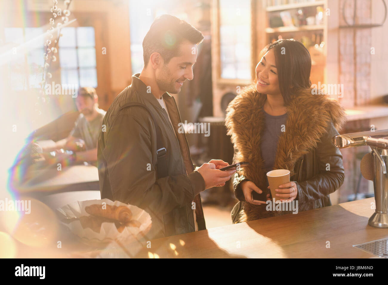 Couple with cell phone and coffee at counter in cafe Stock Photo - Alamy