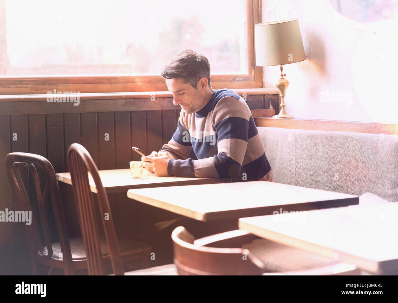 Man texting with cell phone at table in sunny cafe window Stock Photo ...