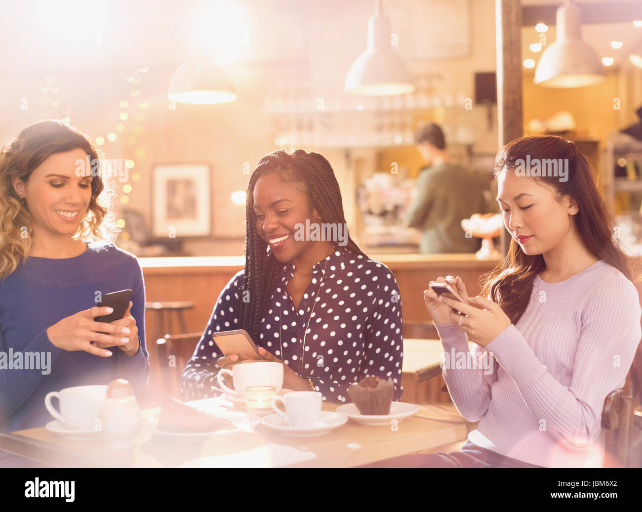 Women friends texting with cell phones at cafe table Stock Photo - Alamy