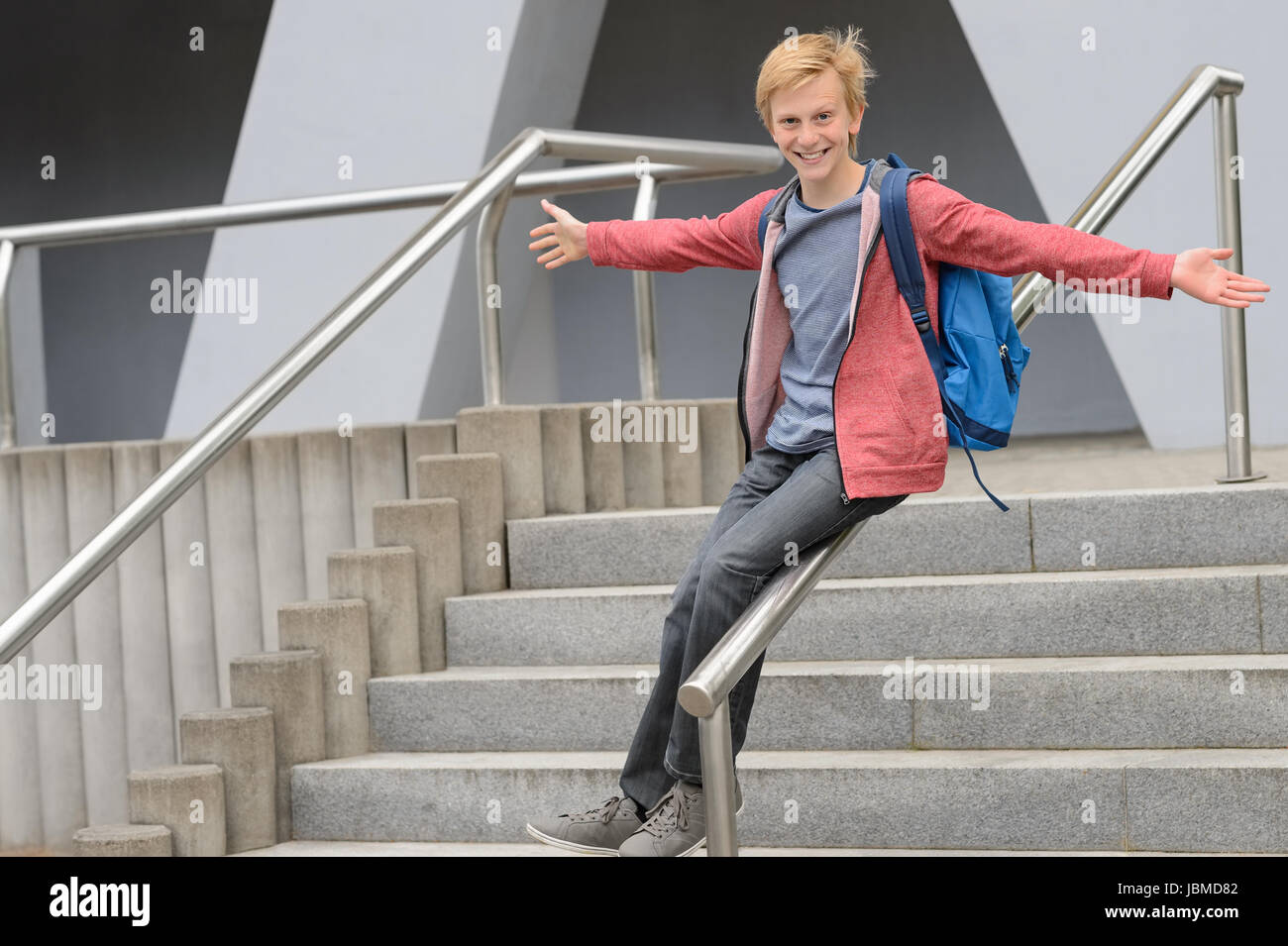 Playful teenage student sliding down railing on school stairway Stock ...