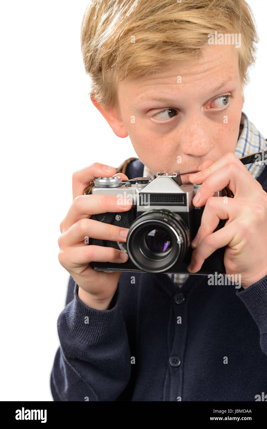 Suspicious teenage boy holding retro camera against white background ...