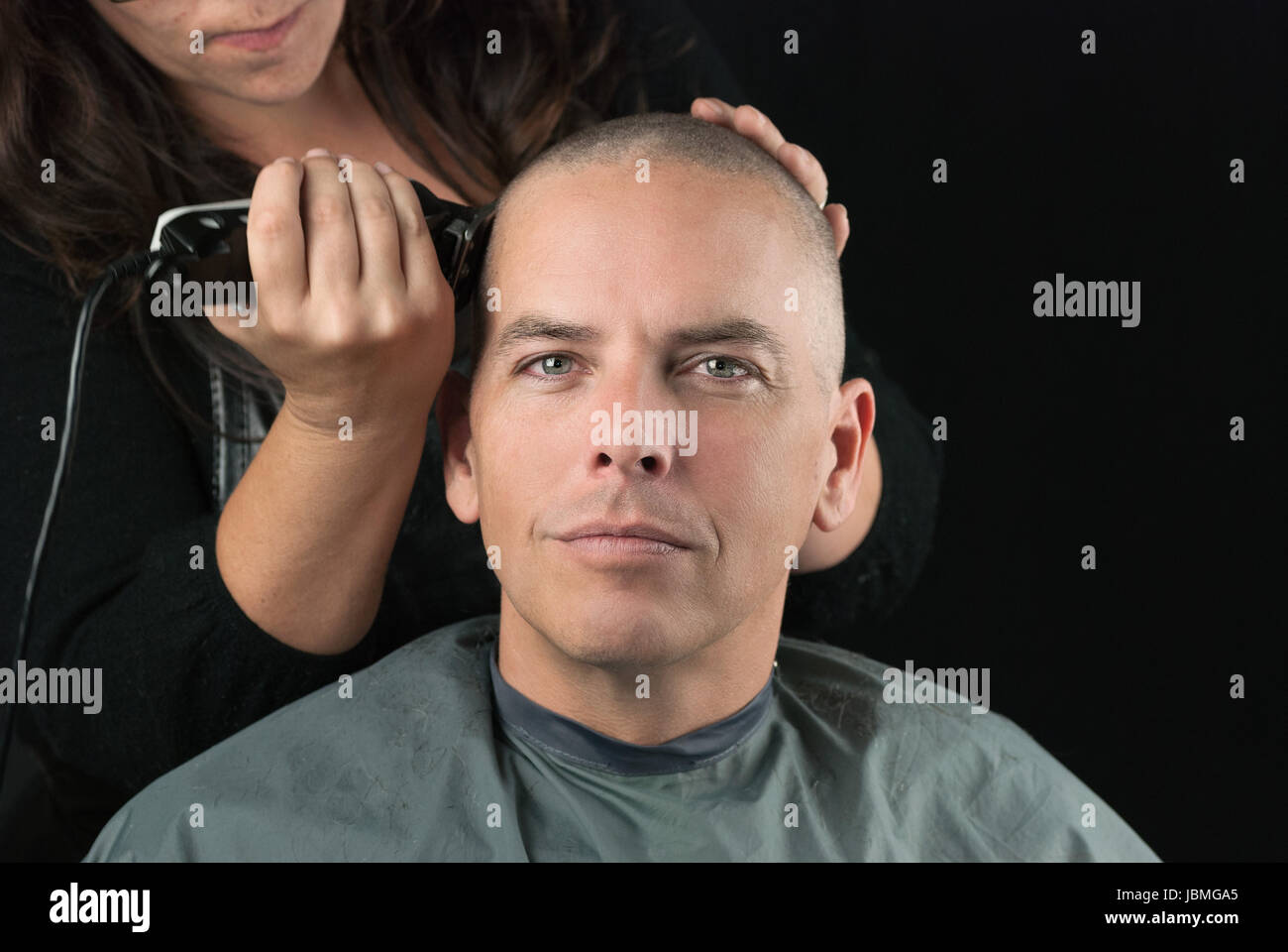 Close-up of a hair stylist using clippers to shave her Clients head ...