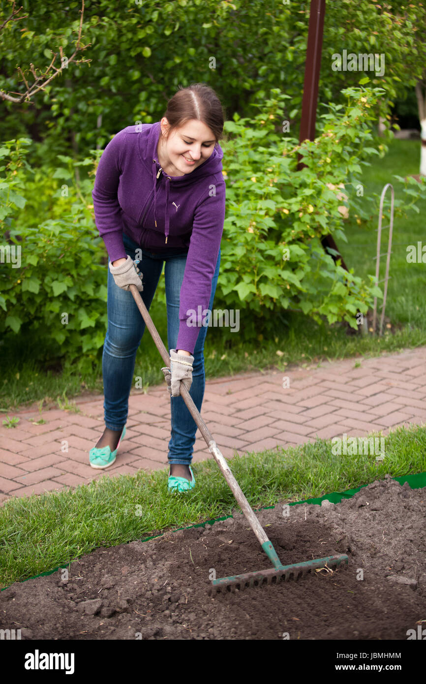 Photo of beautiful woman working with rake on garden bed Stock Photo ...