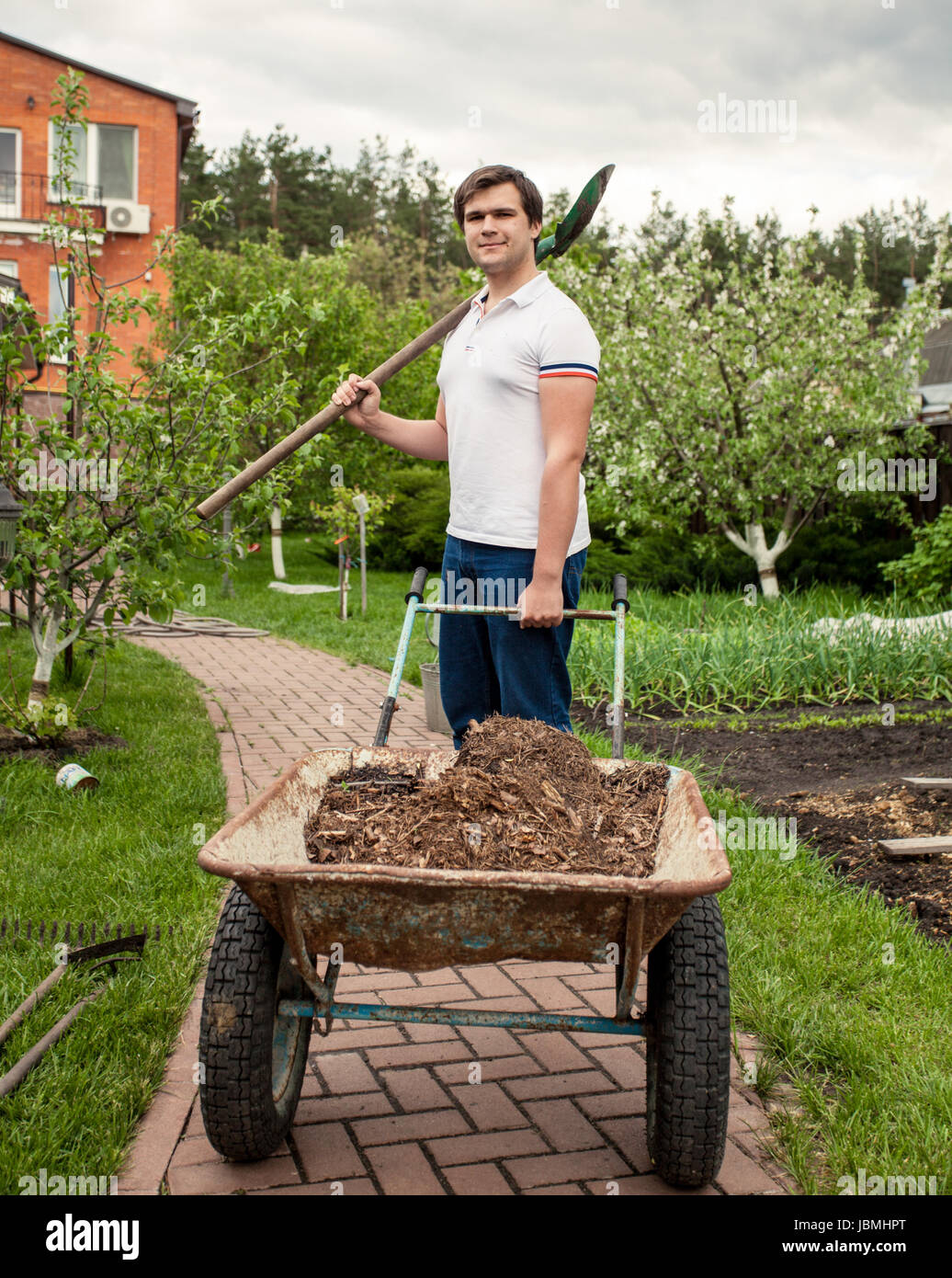 Portrait of smiling man with spade and garden wheelbarrow Stock Photo ...