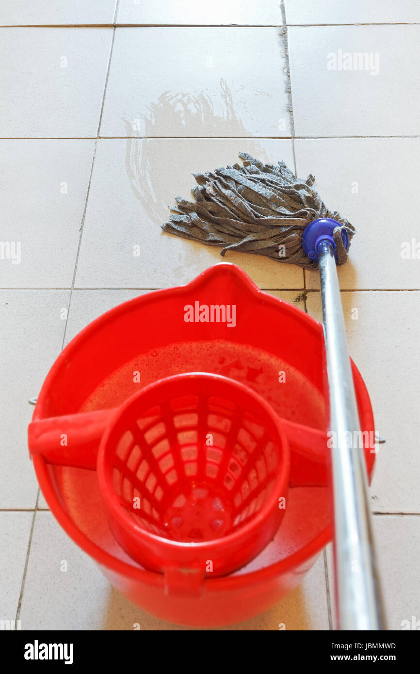 mopping the tile floor by swab and red bucket with foamy water Stock ...