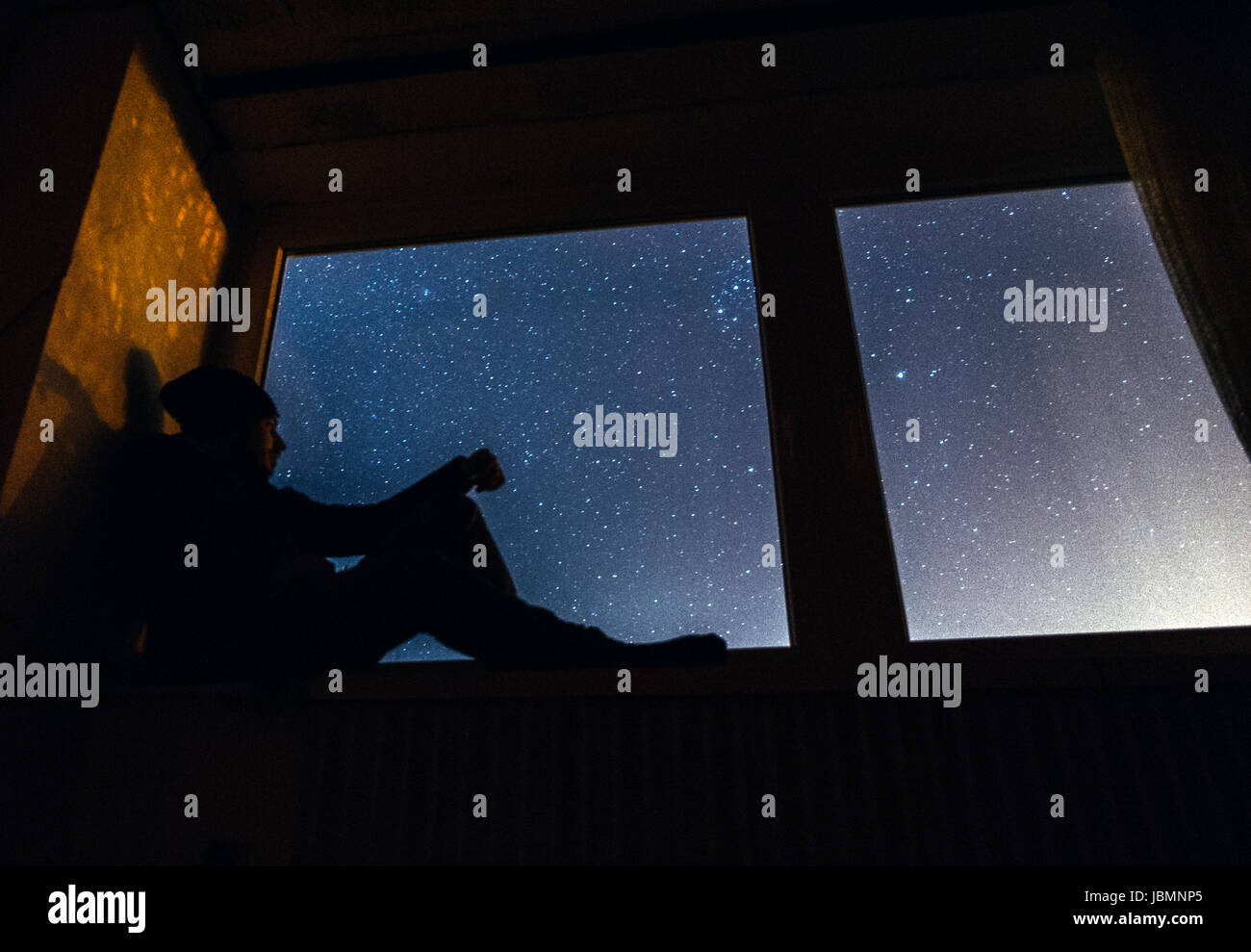 Man sitting in windows at night Stock Photo - Alamy