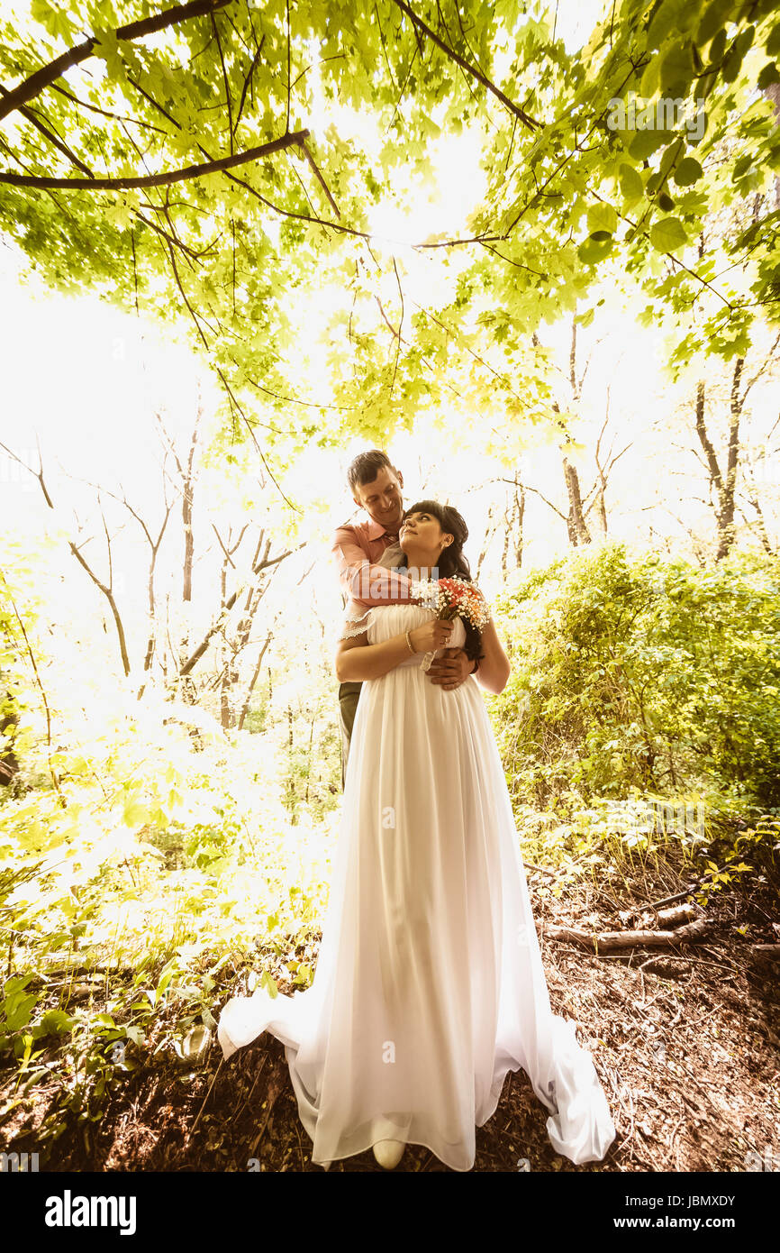 Toned photo of beautiful newly married couple hugging under tree at ...