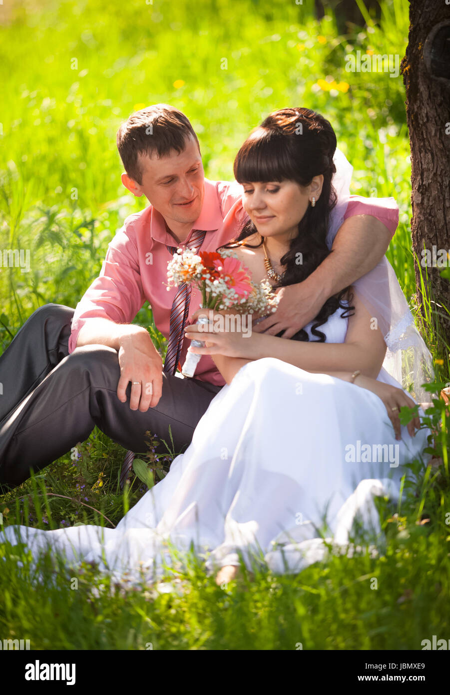 Portrait of young groom presenting flower to bride under tree at park ...