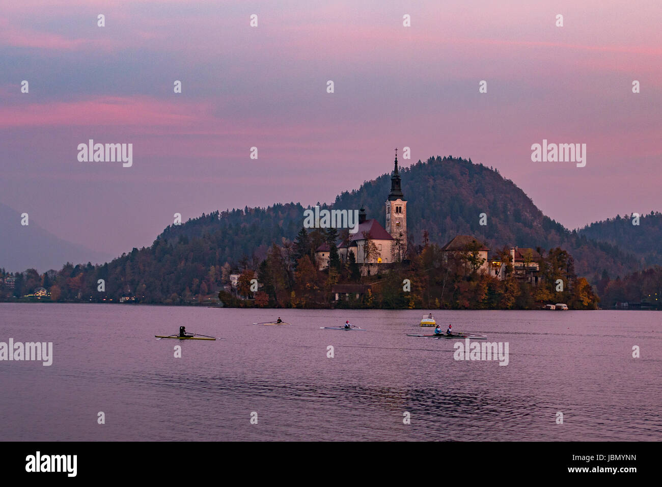 People rowing on Lake Bled at twilight Stock Photo - Alamy