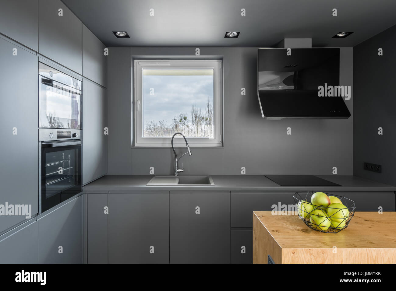 Gray kitchen with window, modern cupboards and island Stock Photo - Alamy