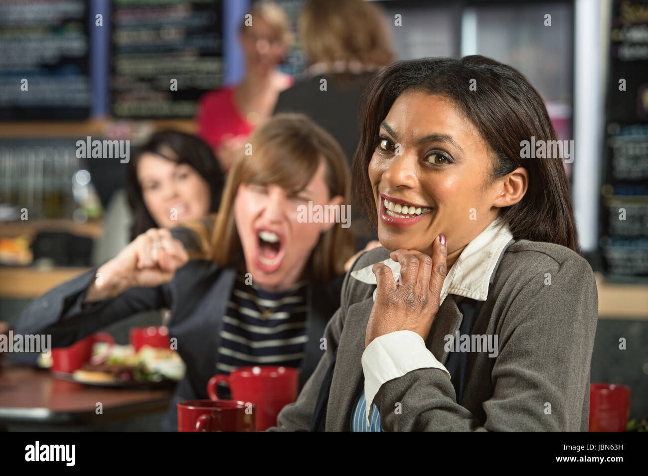 Angry lady behind giggling woman in coffee house Stock Photo - Alamy