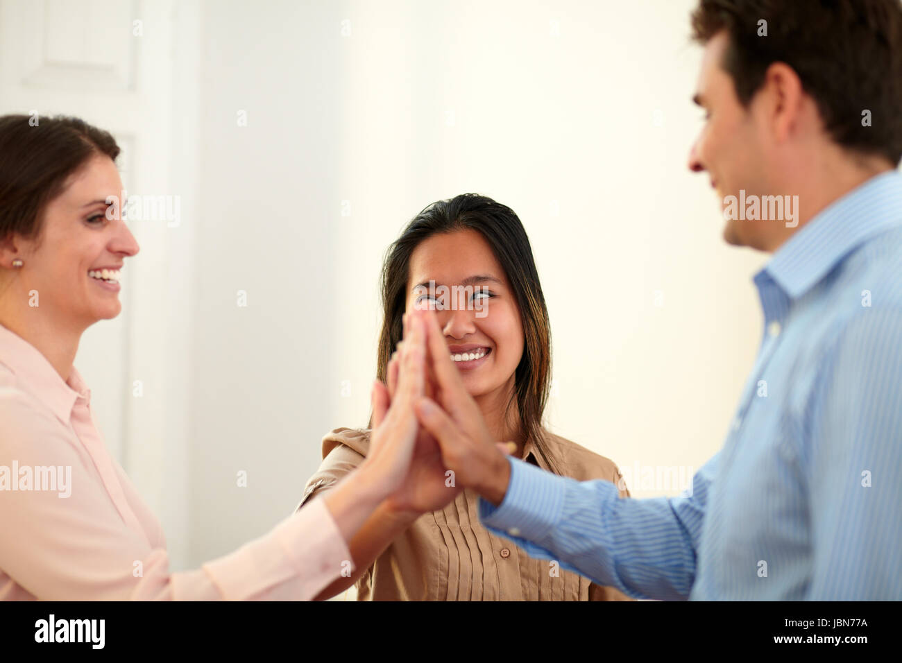 Portrait of male and female colleagues huddle their hands as unity sign ...
