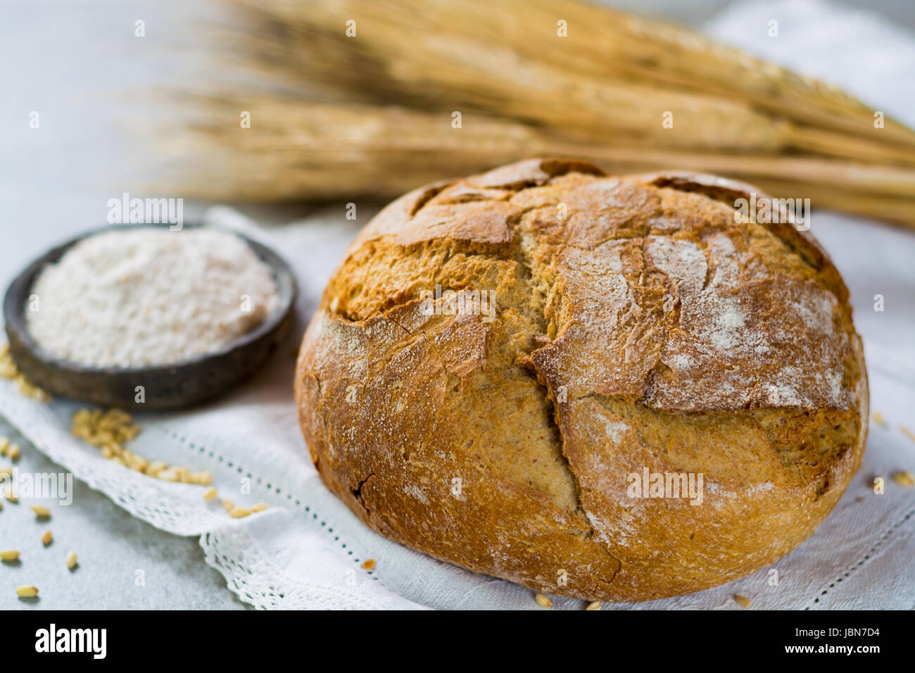 Freshly baked traditional wheat bread and wheat ears on white linnen ...