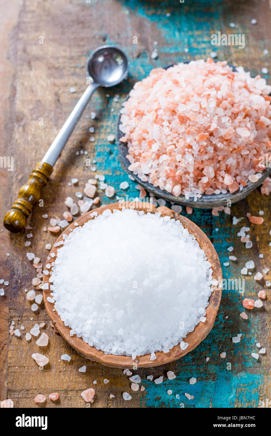 Different types of natural salt in stone bowls on wooden surface. White ...