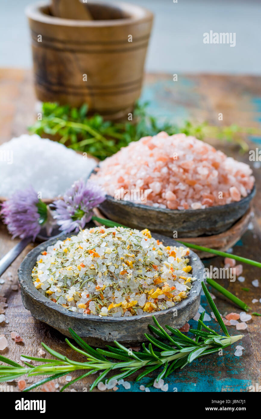 Different types of natural salt in stone bowls on wooden surface. White ...