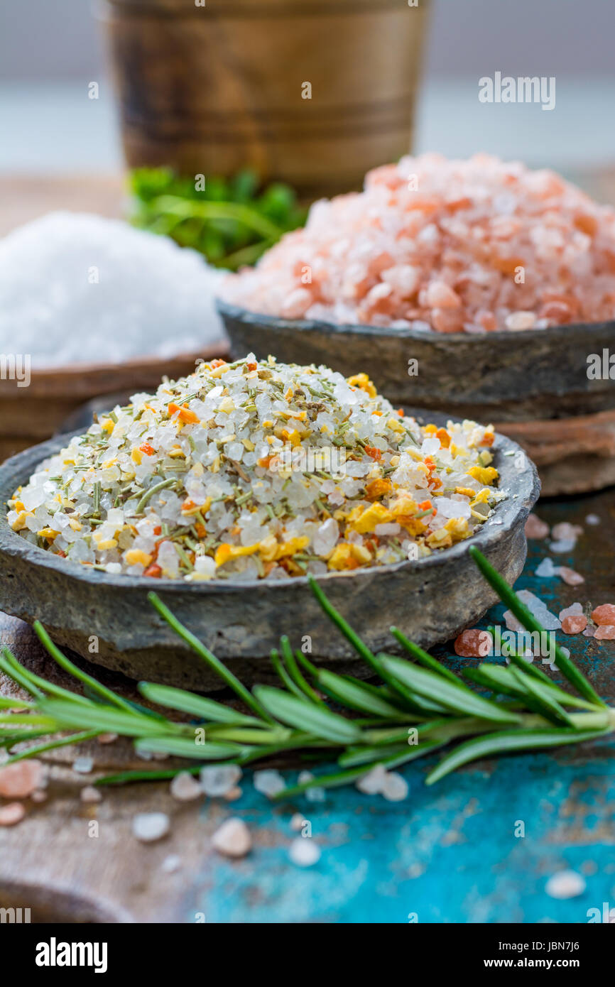 Different types of natural salt in stone bowls on wooden surface. White ...