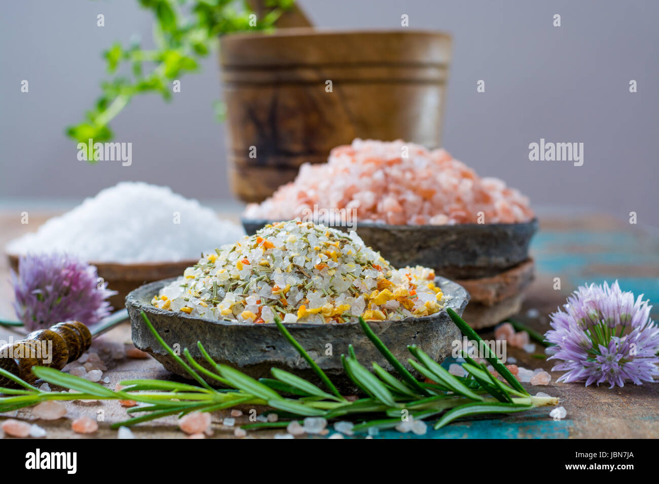 Different types of natural salt in stone bowls on wooden surface. White ...