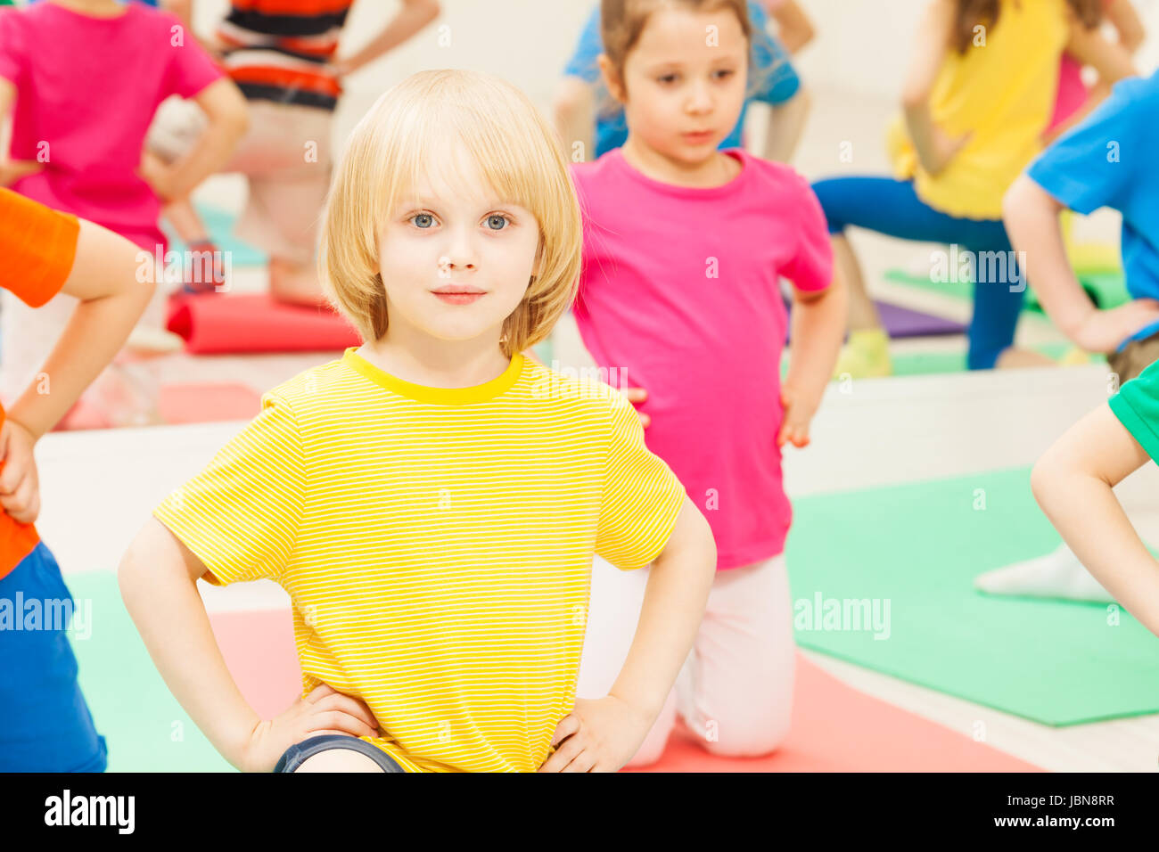 Portrait of Caucasian kid boy kneeling with hands on waist, practicing ...