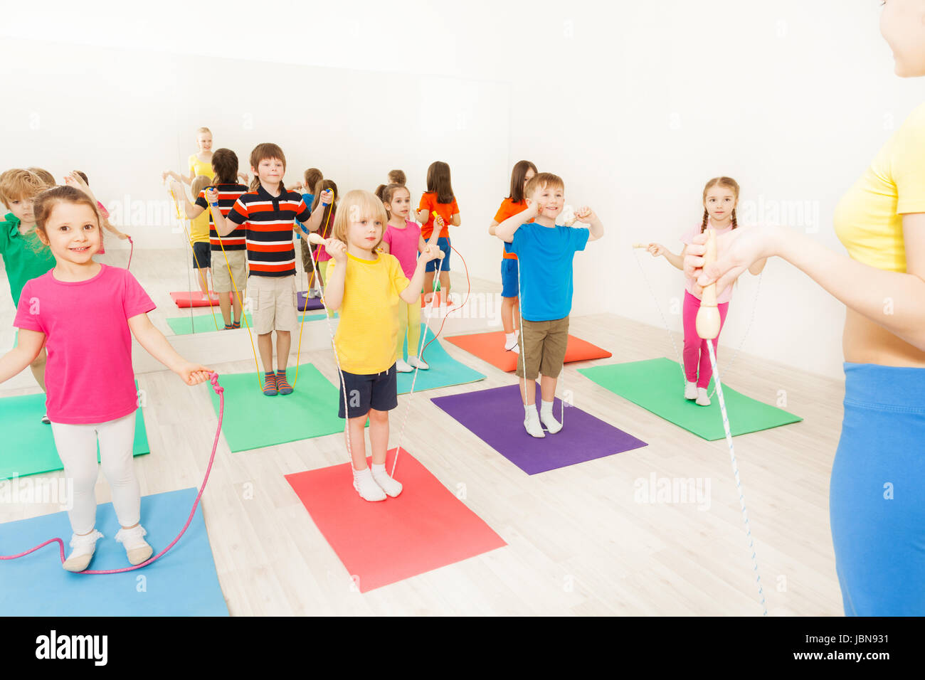 Sports coach teaching kids jumping with skipping rope in gym Stock ...
