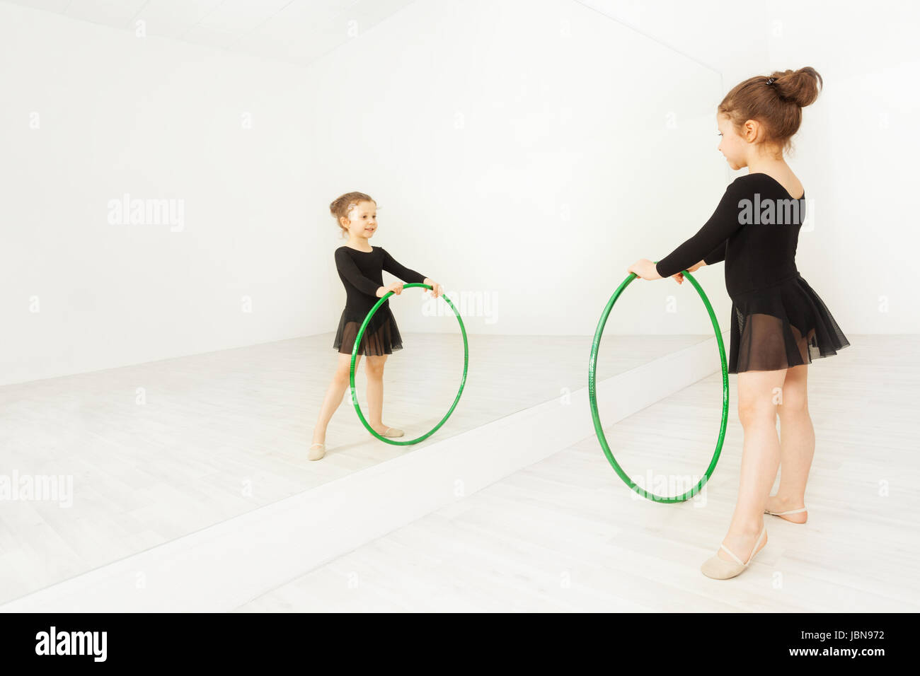 Reflection of five years old girl in black dancewear practicing ...