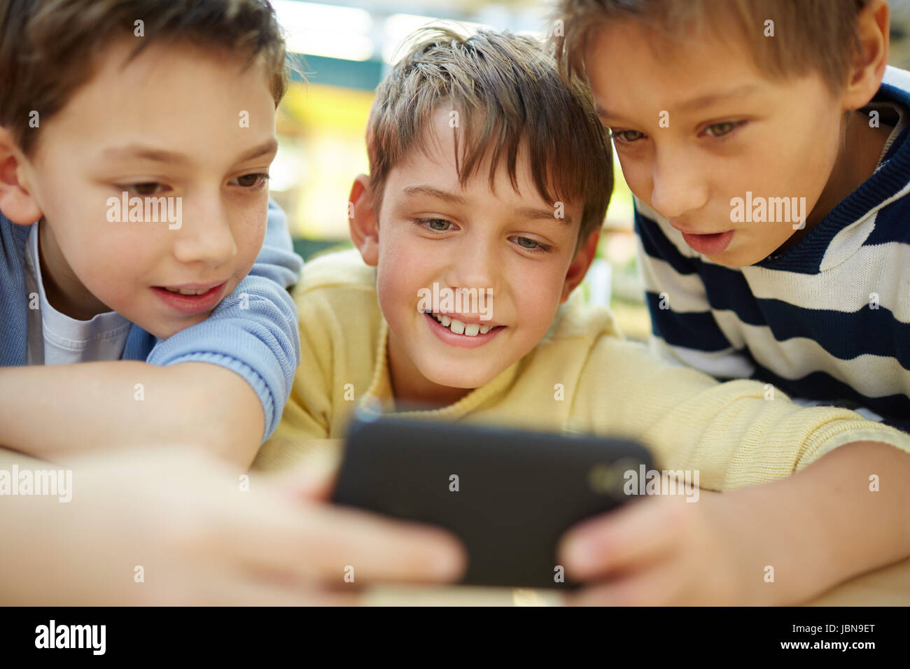Three friends using a new smartphone Stock Photo - Alamy