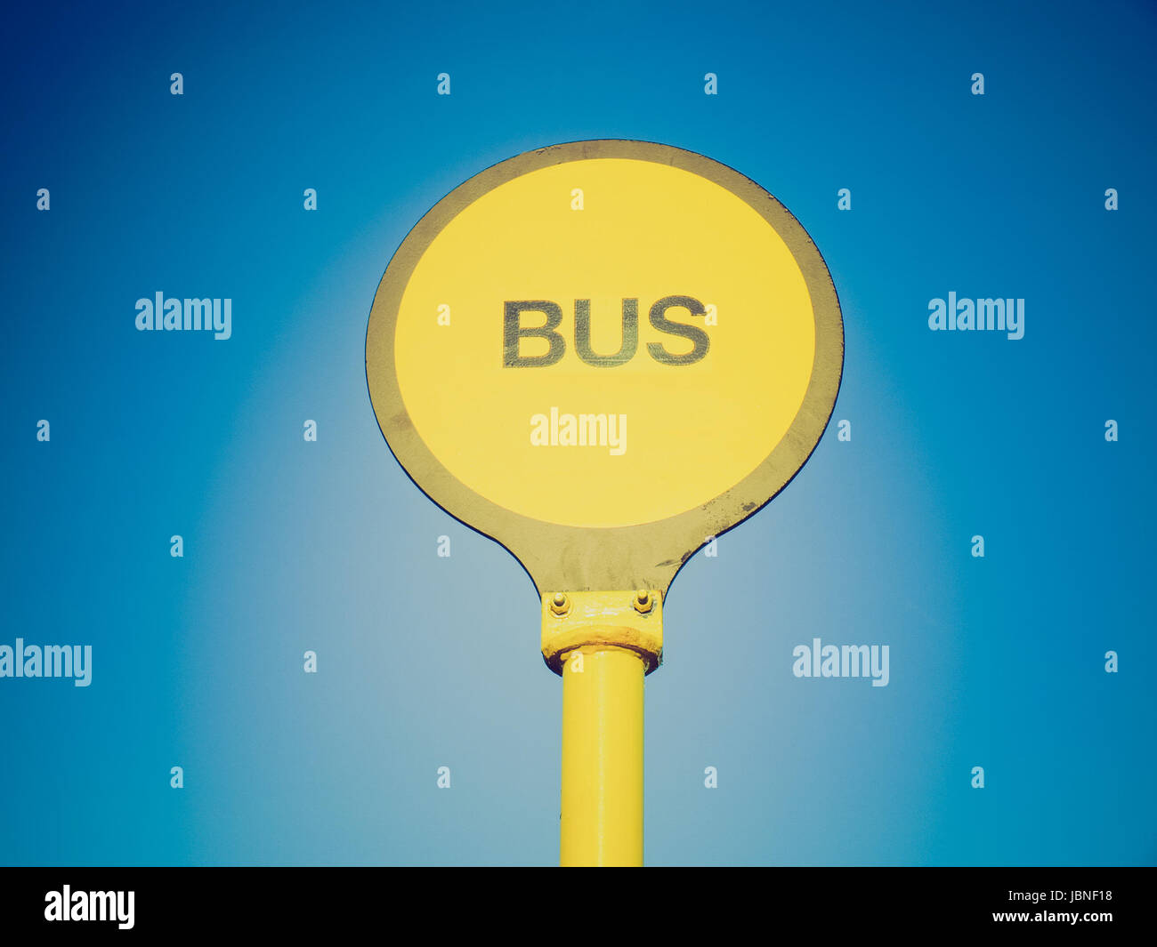 Vintage retro looking Yellow bus stop sign over blue sky background ...