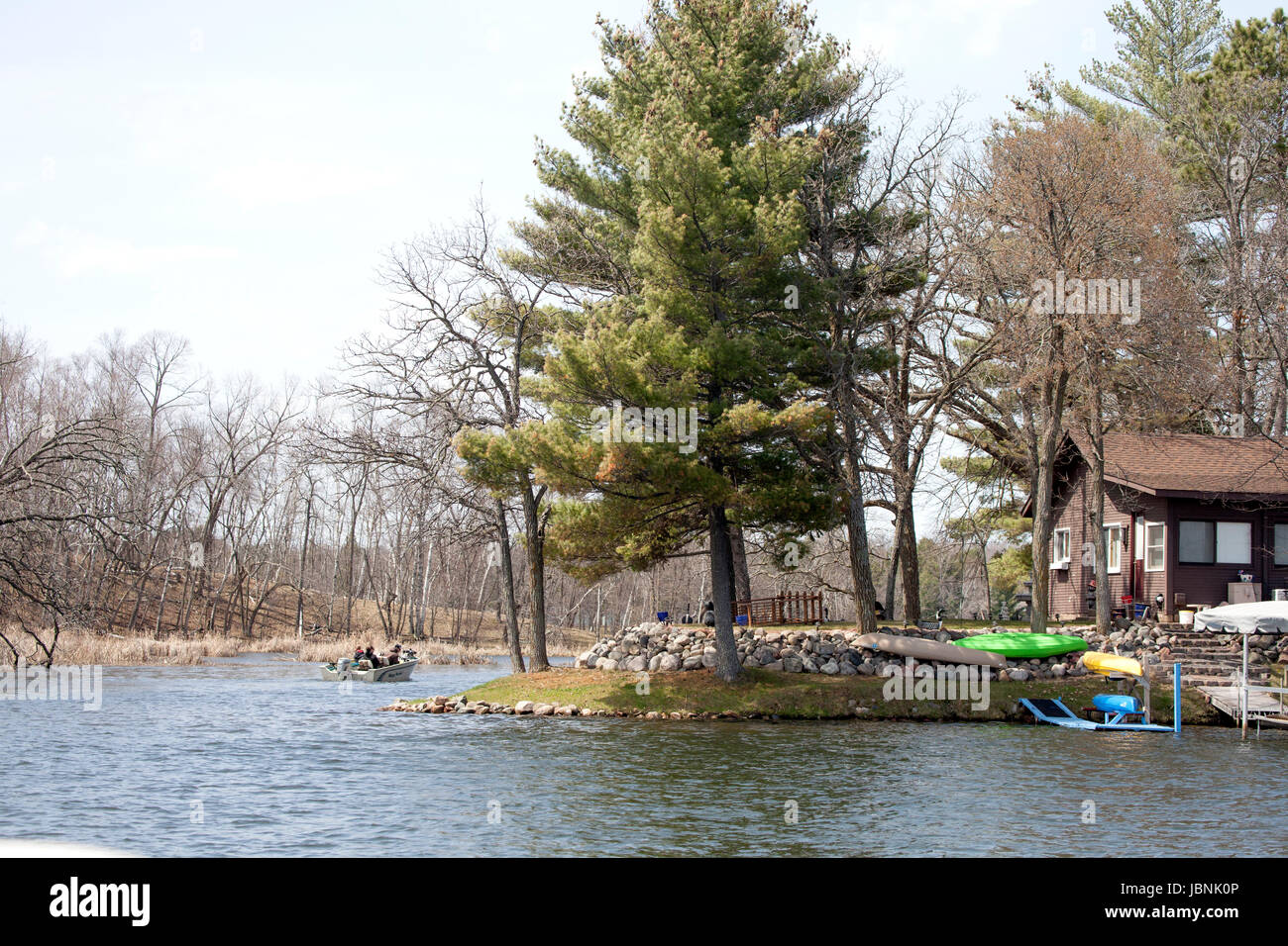 Fishing boat on lake channel and cabin with field stone by the shore ...