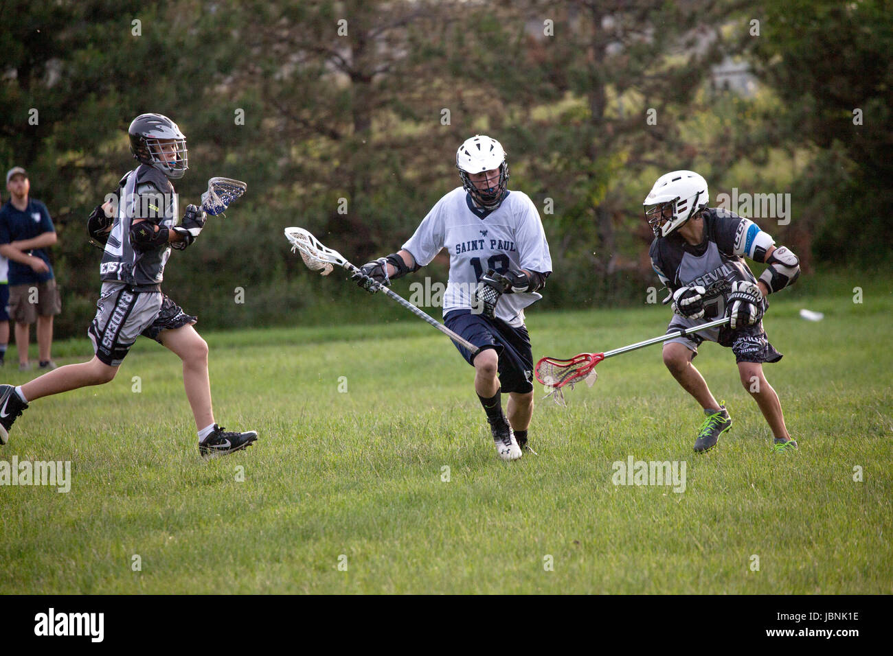 Lacrosse players chasing opponent running with ball in stick pocket. St ...