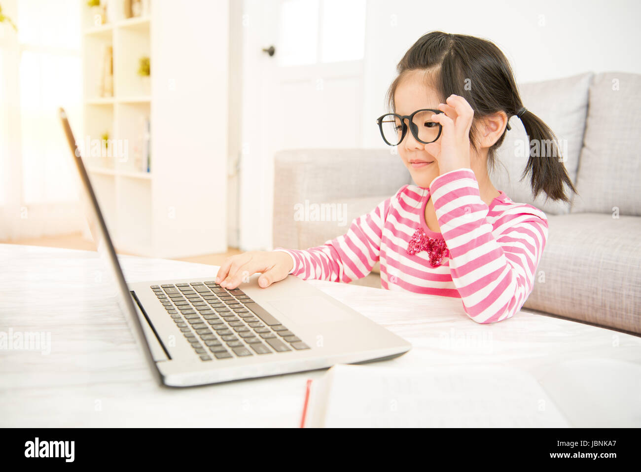 Smart little asian chinese girl wearing big glasses while using her ...