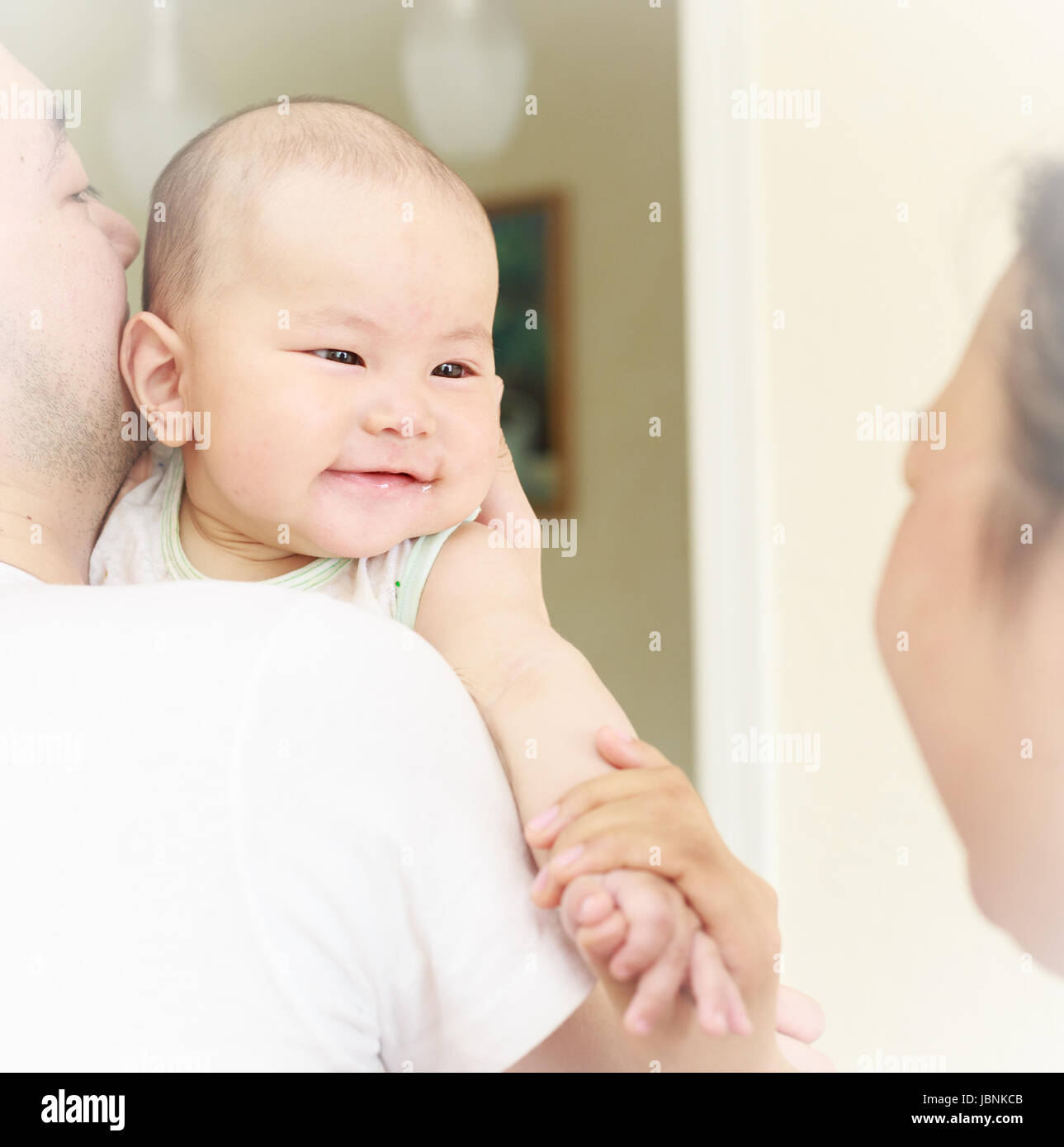 A baby leaned on his father's shoulder to look at his mother Stock ...