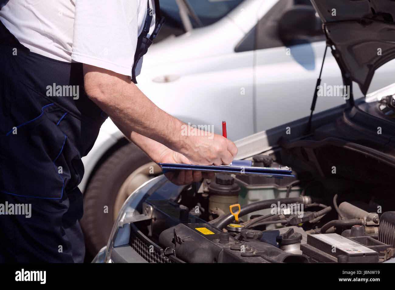 Auto mechanic checking car engine and writing on the clipboard Stock ...