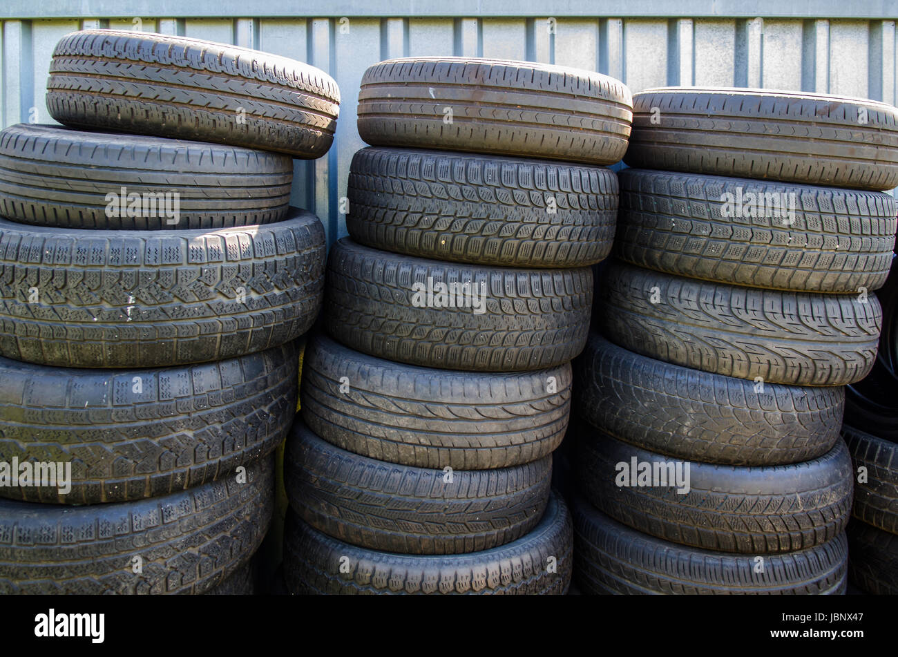 three stacks of used old tires in front of a container Stock Photo - Alamy
