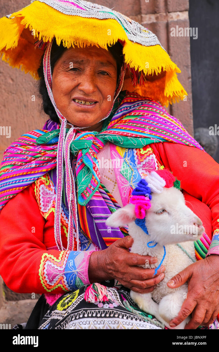 Local woman in traditional dress holding lamb in the street of Cusco ...