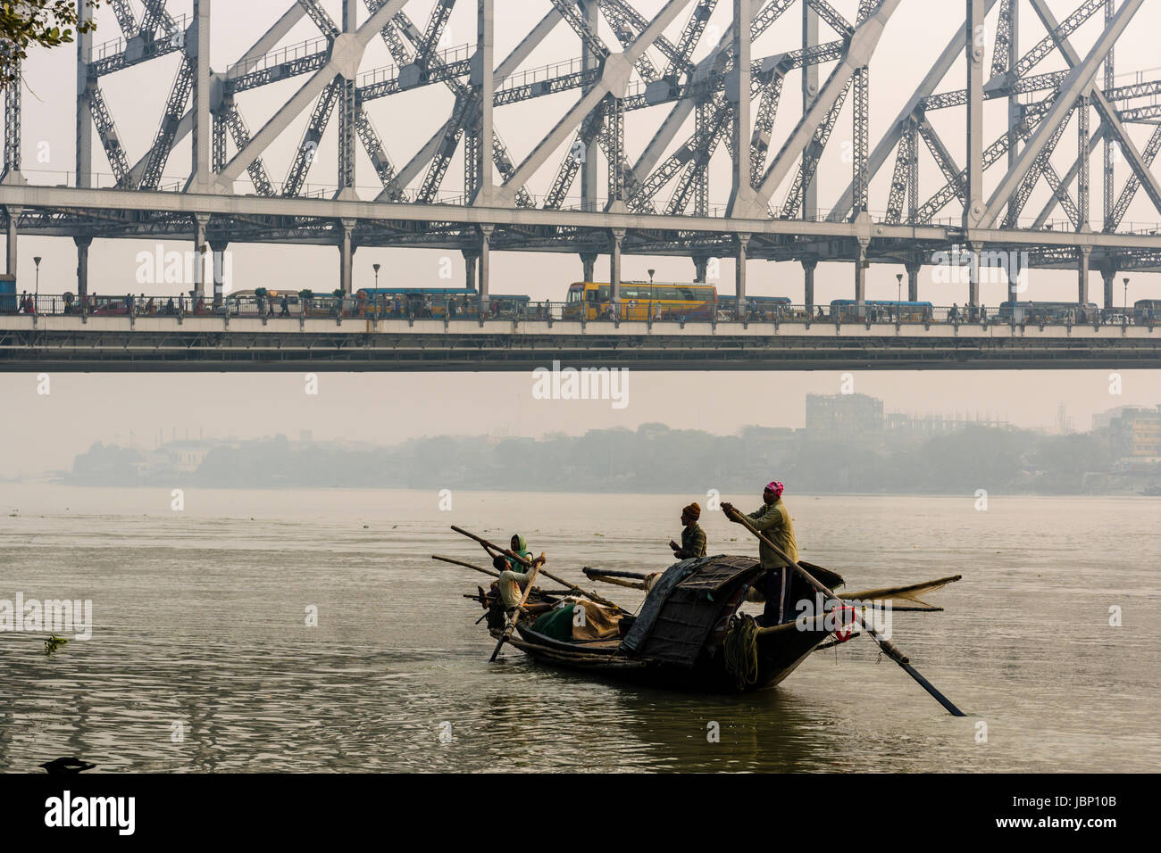The steel construction of Howrah Bridge in Kolkata, a fishermans boat ...