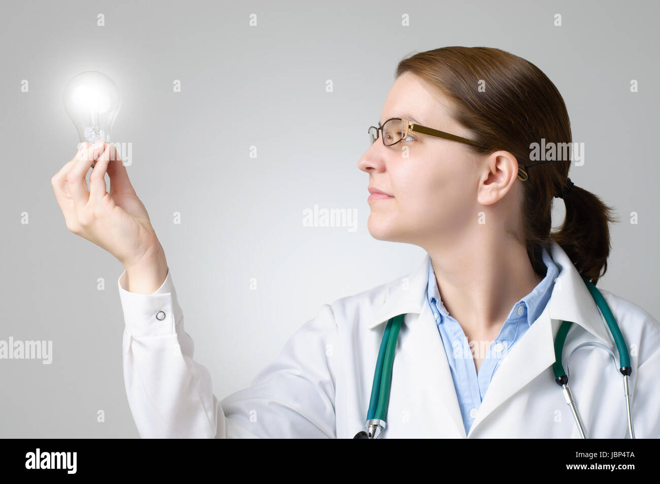 Female doctor holding and looking a glowing light bulb Stock Photo - Alamy