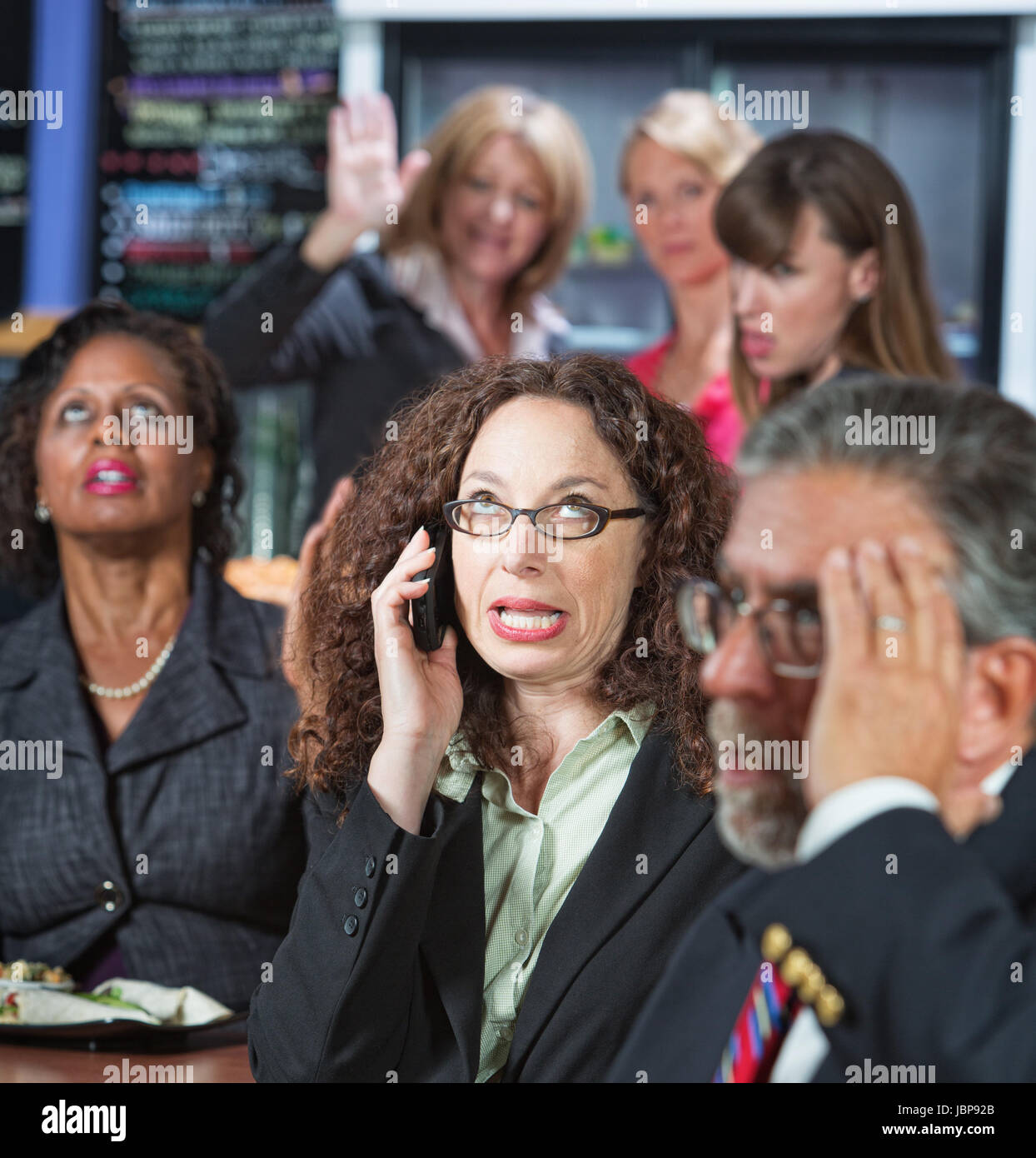 Loud woman on cell phone in cafeteria with coworkers Stock Photo - Alamy