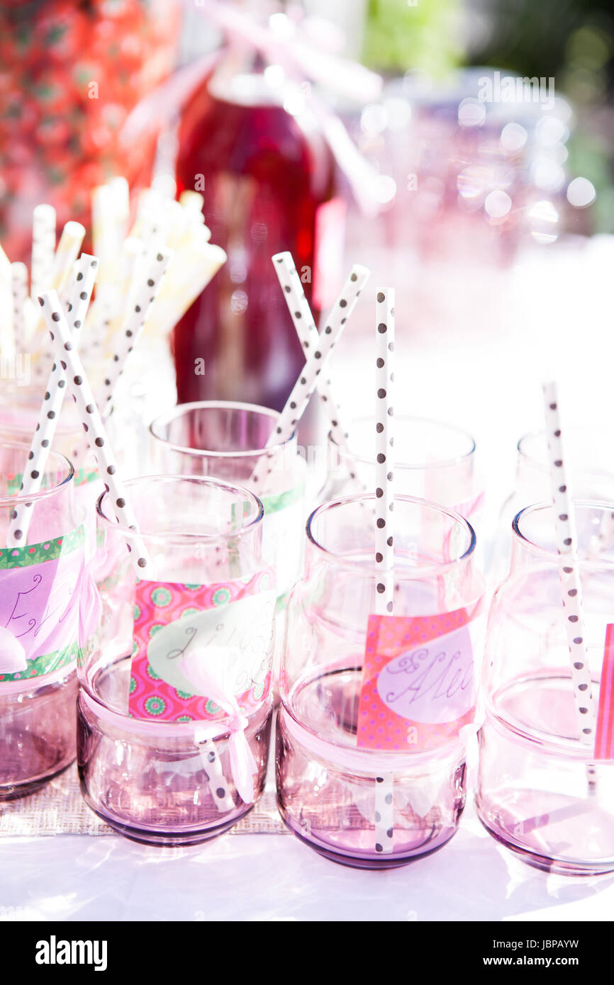 Closeup of decorative pink colored party glasses with straws on table ...