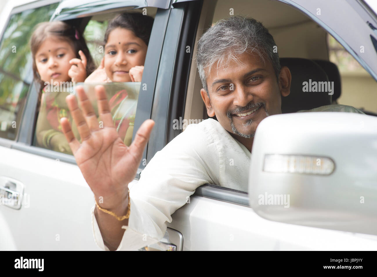 Indian family waving hands and saying goodbye, sitting in car ready to ...