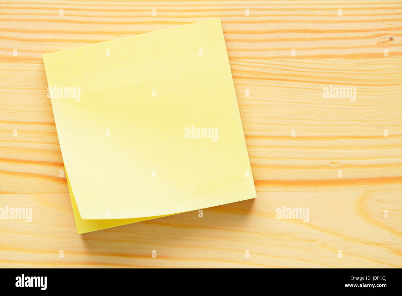 Yellow memo sticker on wooden wall Stock Photo - Alamy