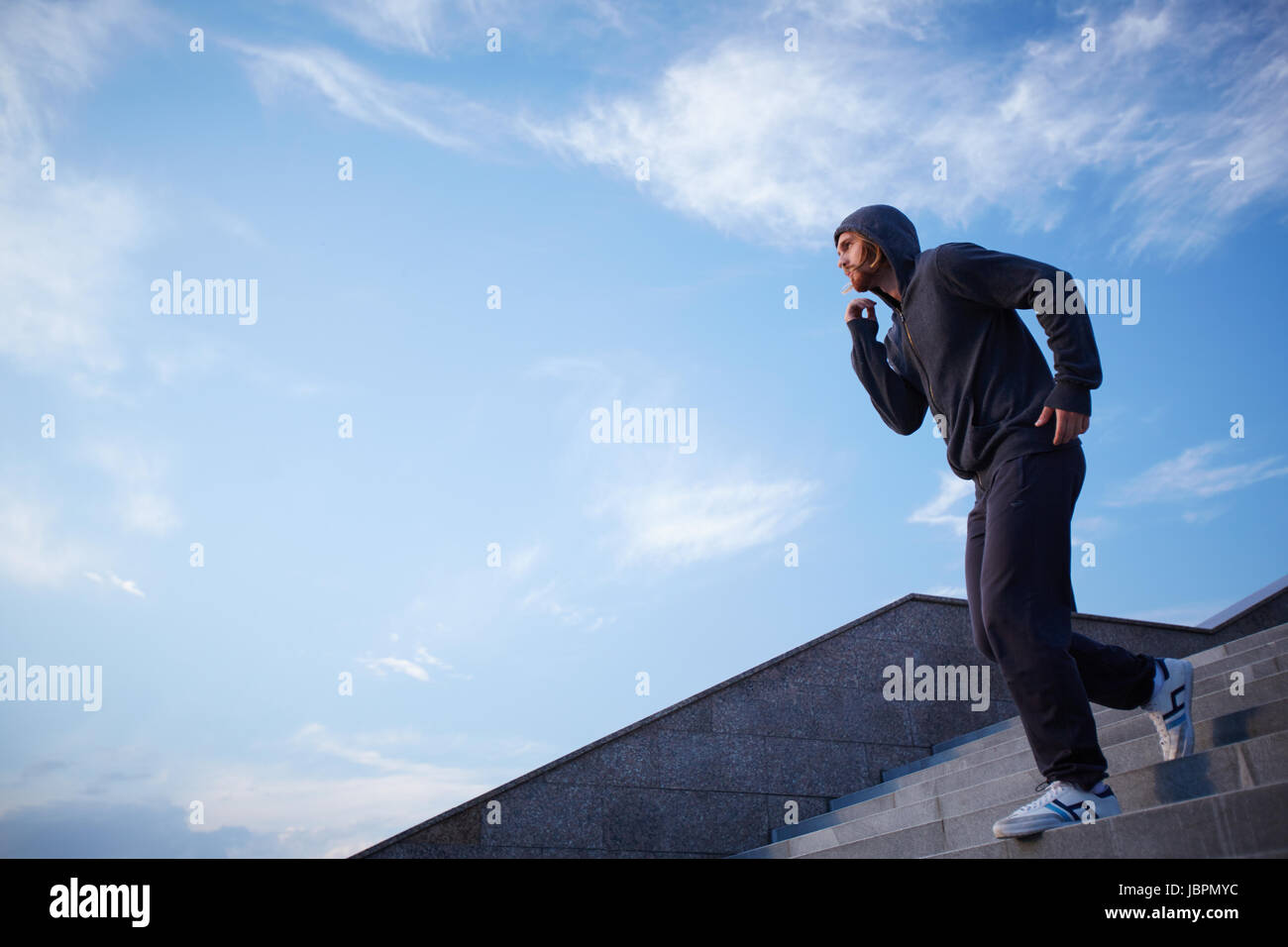 Portrait of young attractive sportsman running down steps against ...