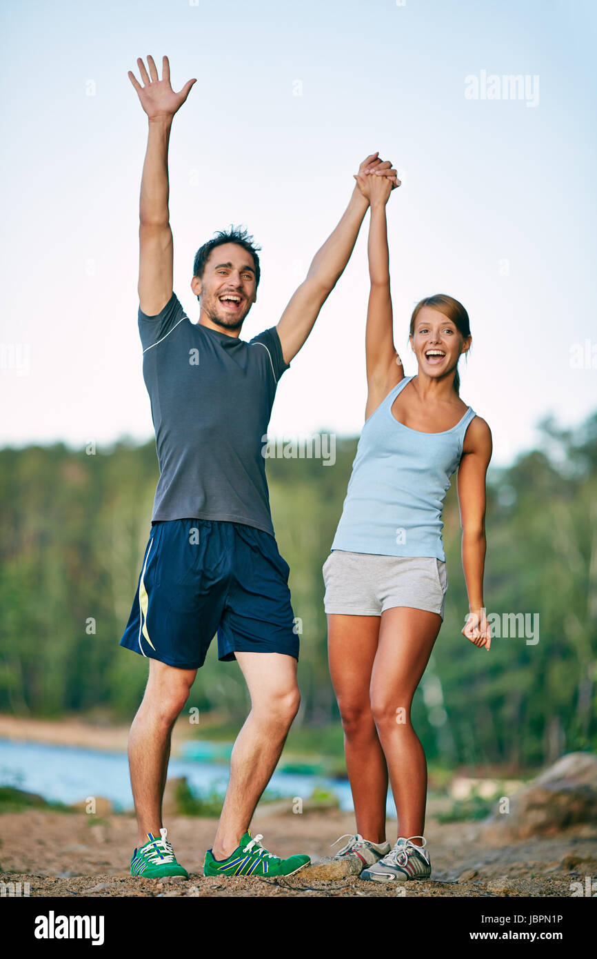 Photo of happy couple raising arms outdoors Stock Photo - Alamy