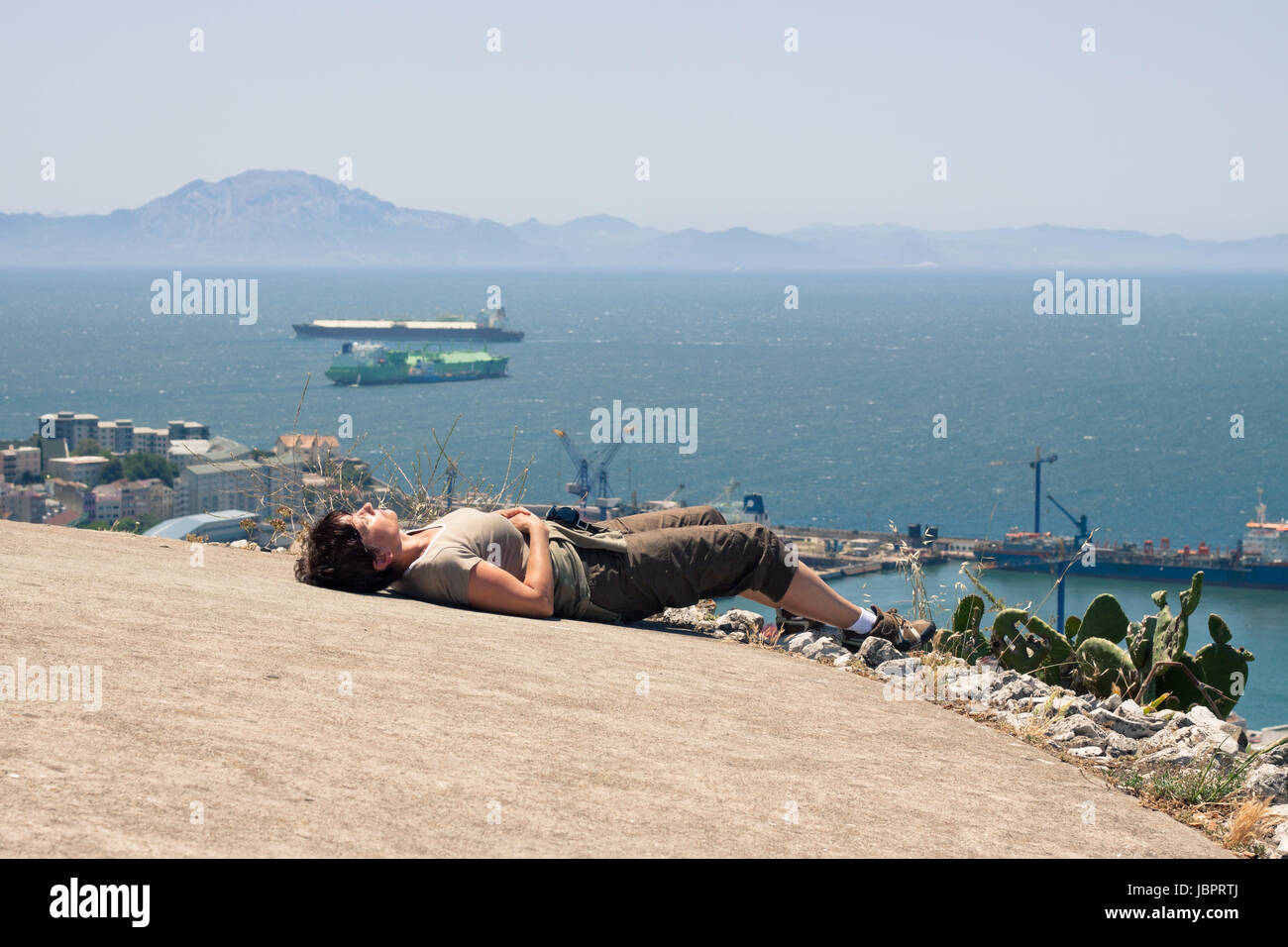 Strait of Gibraltar and middle aged woman tourist resting on the Rock ...