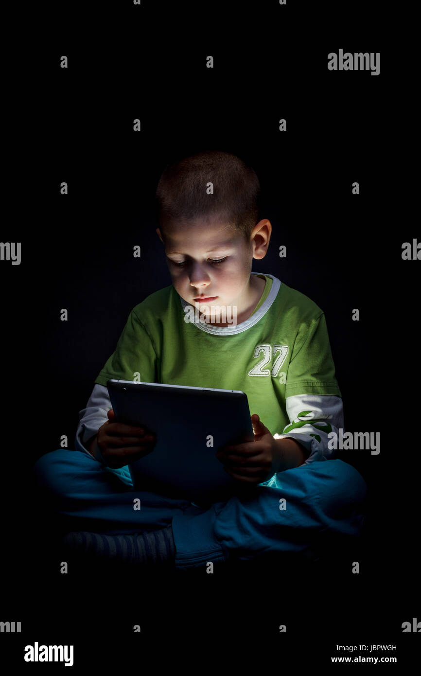 Boy holding tablet PC on black background Stock Photo - Alamy